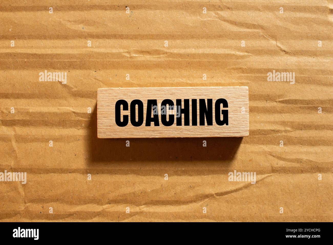 Coaching message written on wooden block with cardboard background ...