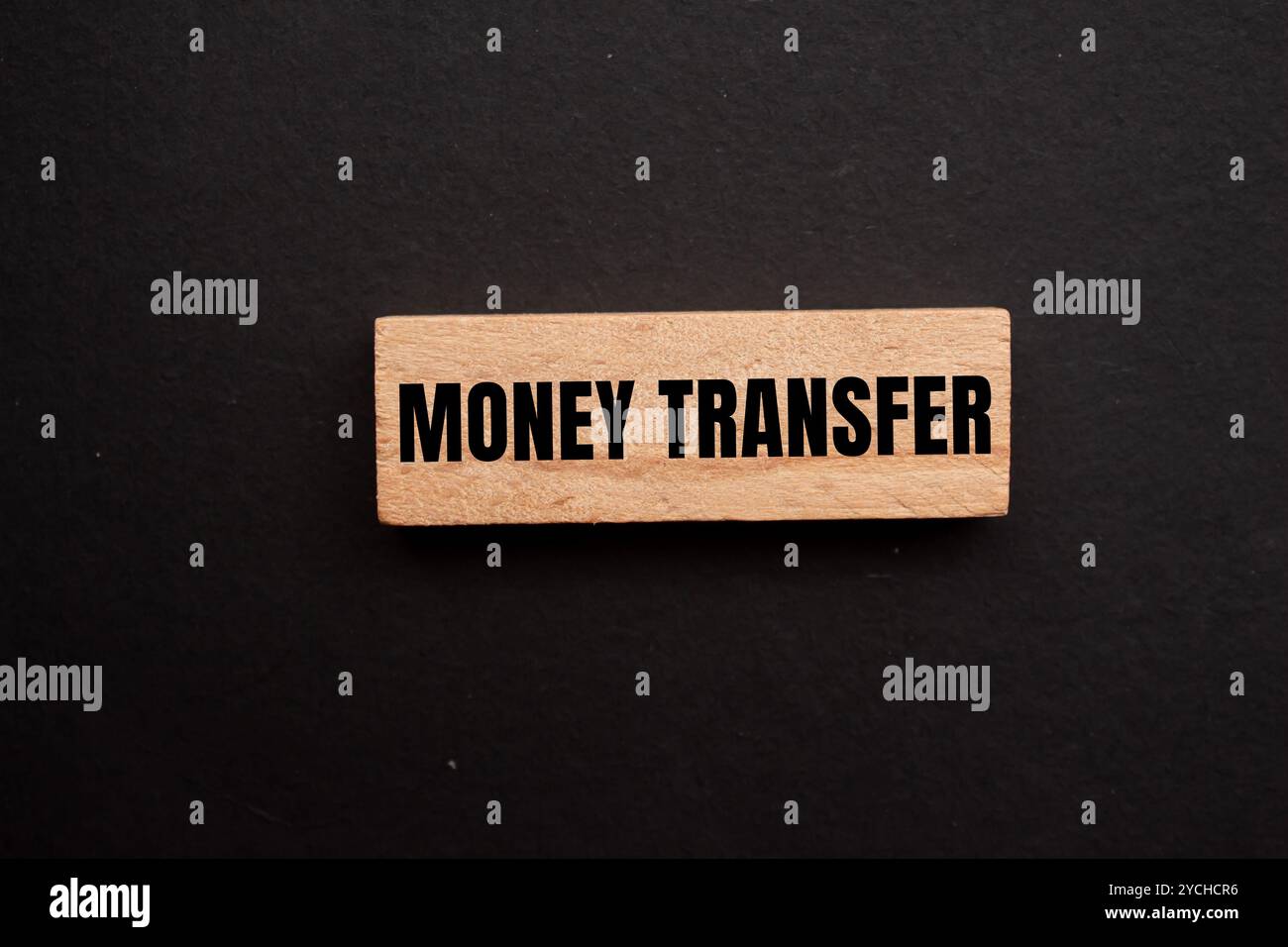 Money transfer message written on wooden block with black background ...
