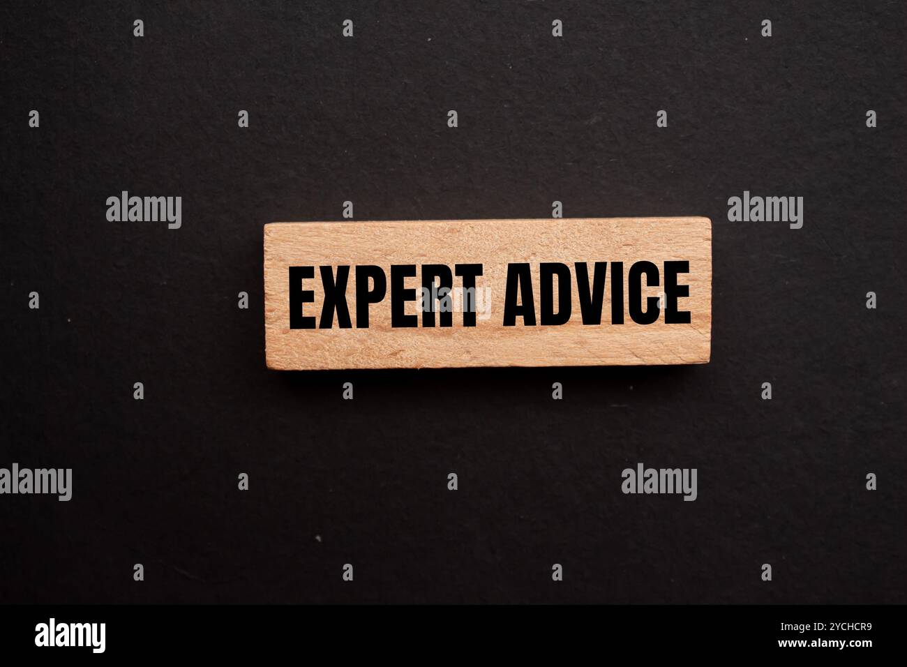 Expert advice message written on wooden block with black background ...