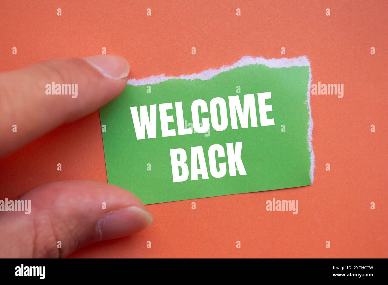 Welcome back message written on ripped green torn paper piece with ...