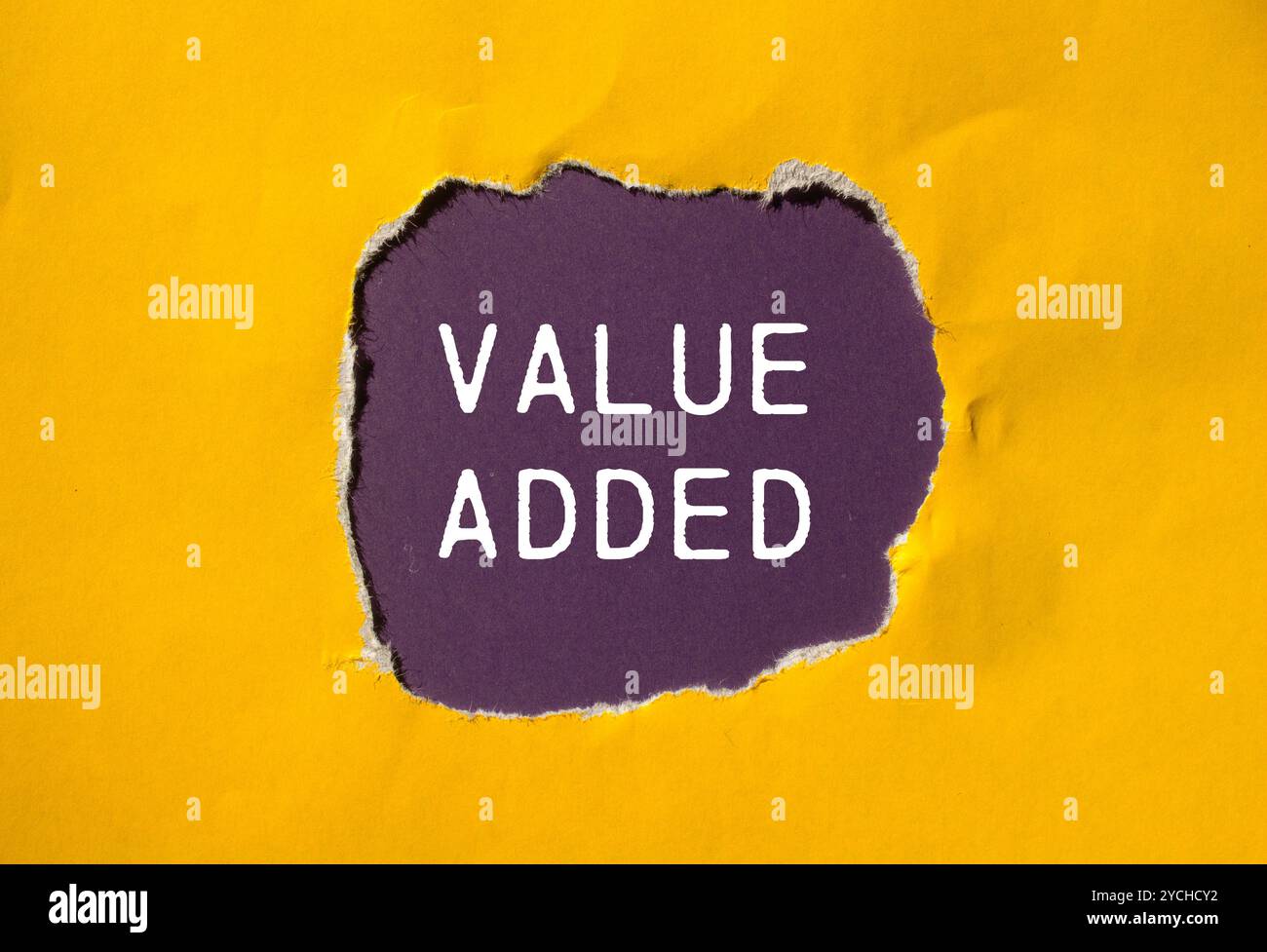 Value added message written on ripped torn yellow paper with purple ...