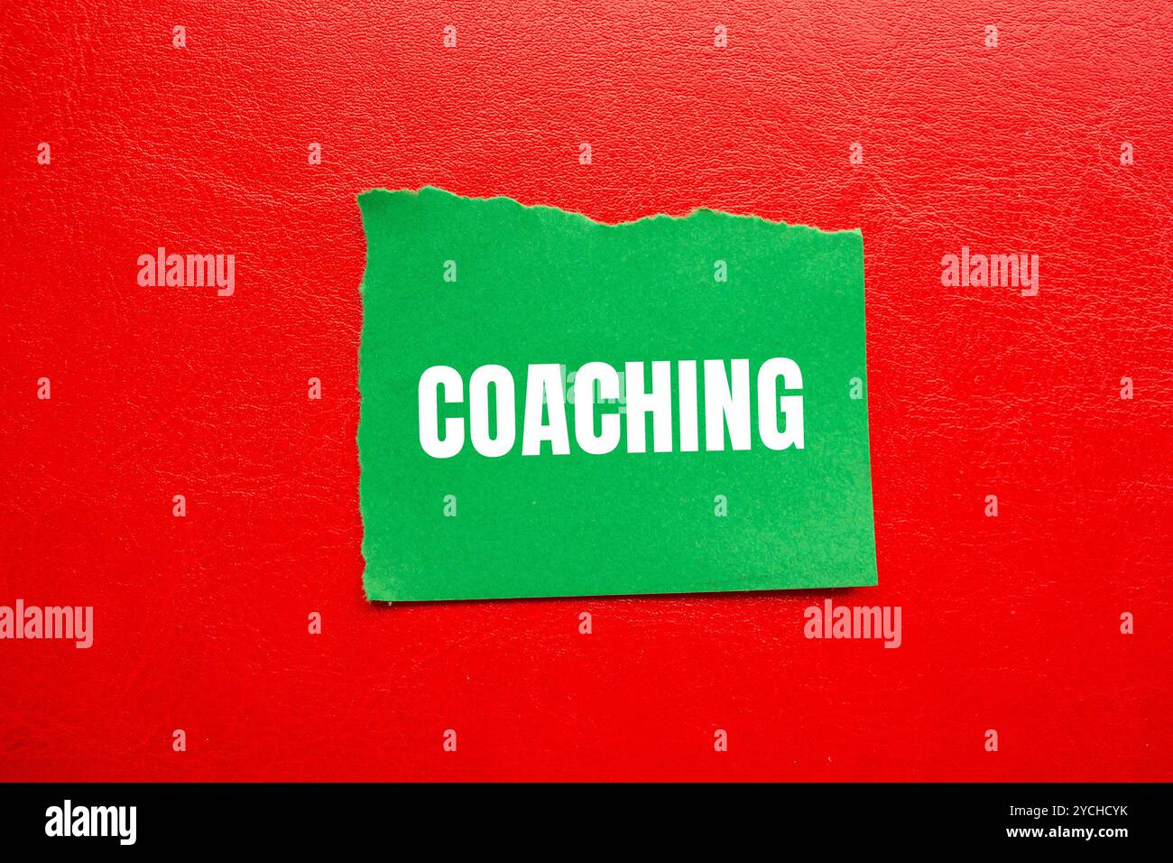 Coaching message written on ripped torn green paper piece with red background. Conceptual ...