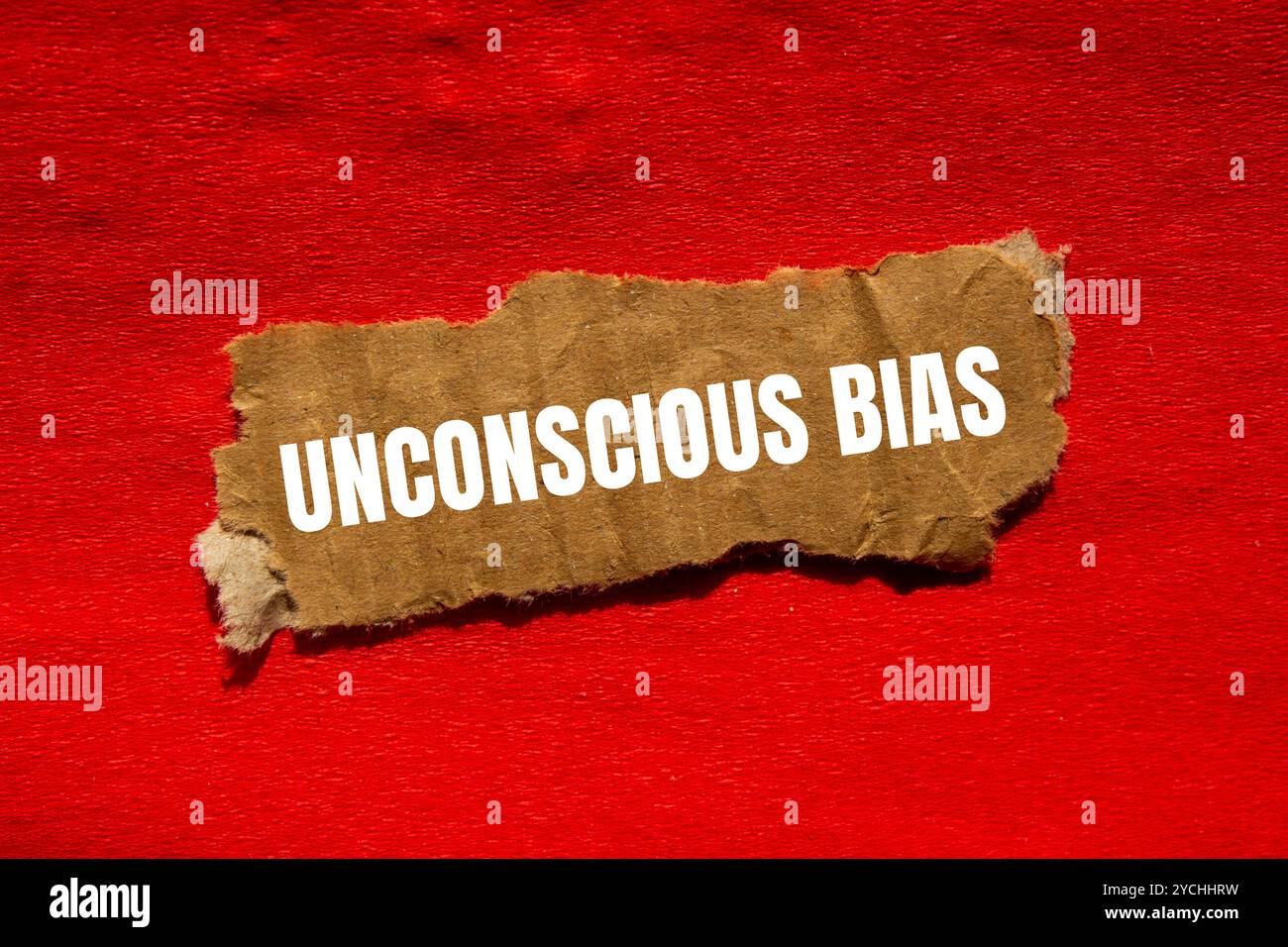 Unconscious bias message written on ripped torn cardbaord paper piece with red background ...