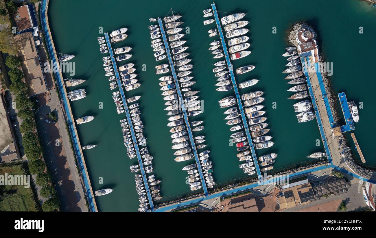 Aerial view of a marina with rows of boats docked in the calm turquoise ...