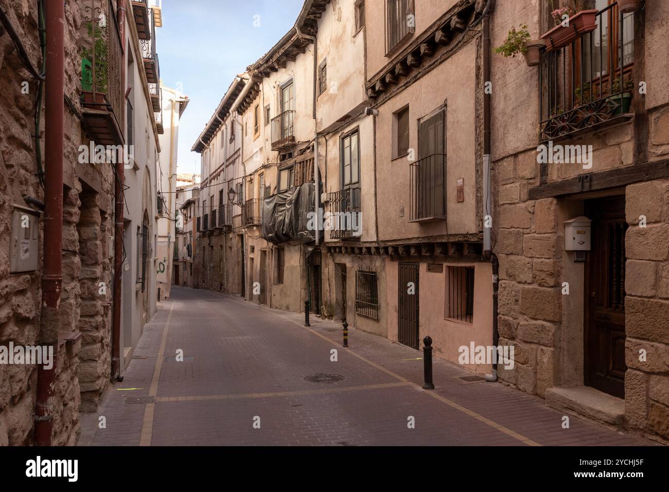 Narrow cobblestone street lined with historic houses in a quiet Spanish ...
