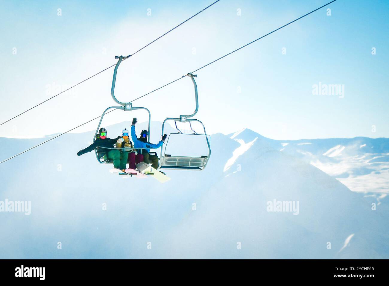 group of cheerful three friends are lifting on ski-lift for skiing ...
