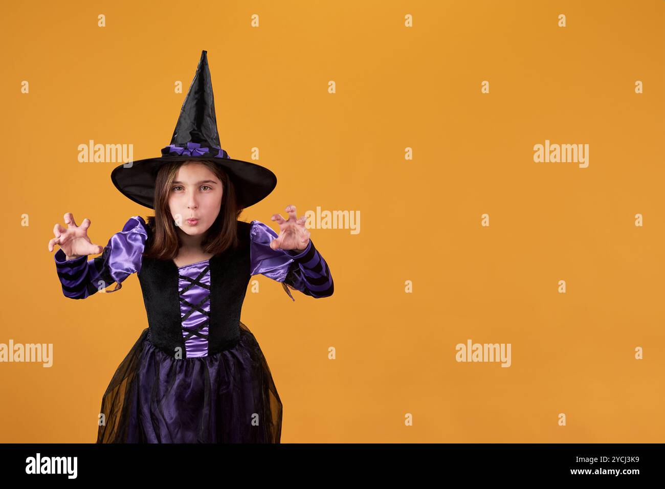 Cute little girl in costume of Halloween witch growling while standing ...