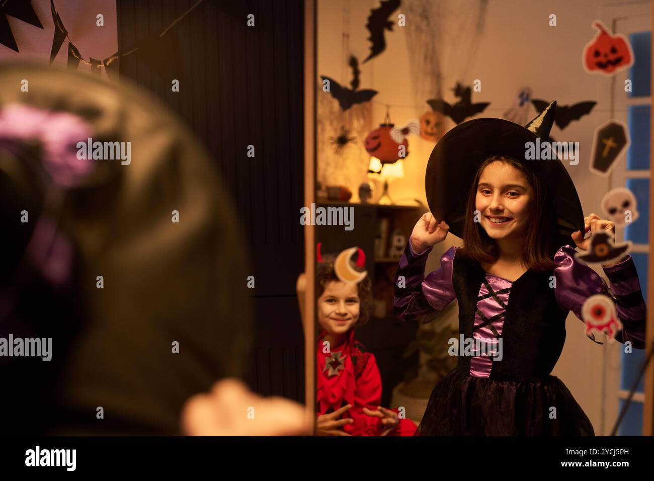 Cute cheerful girl in costume of Halloween witch standing in front of ...