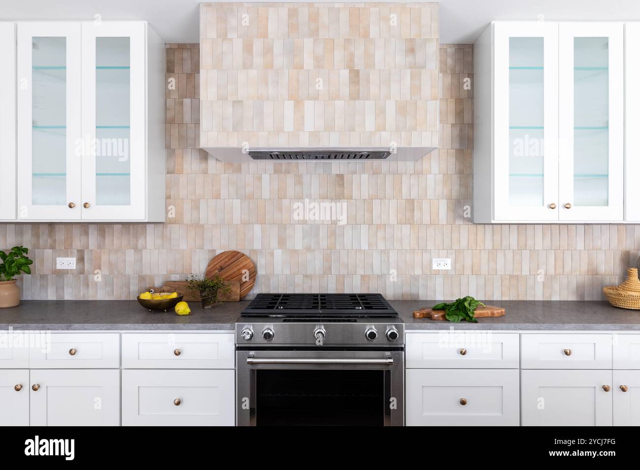 A kitchen oven and range hood detail with brown rectangle tiles ...