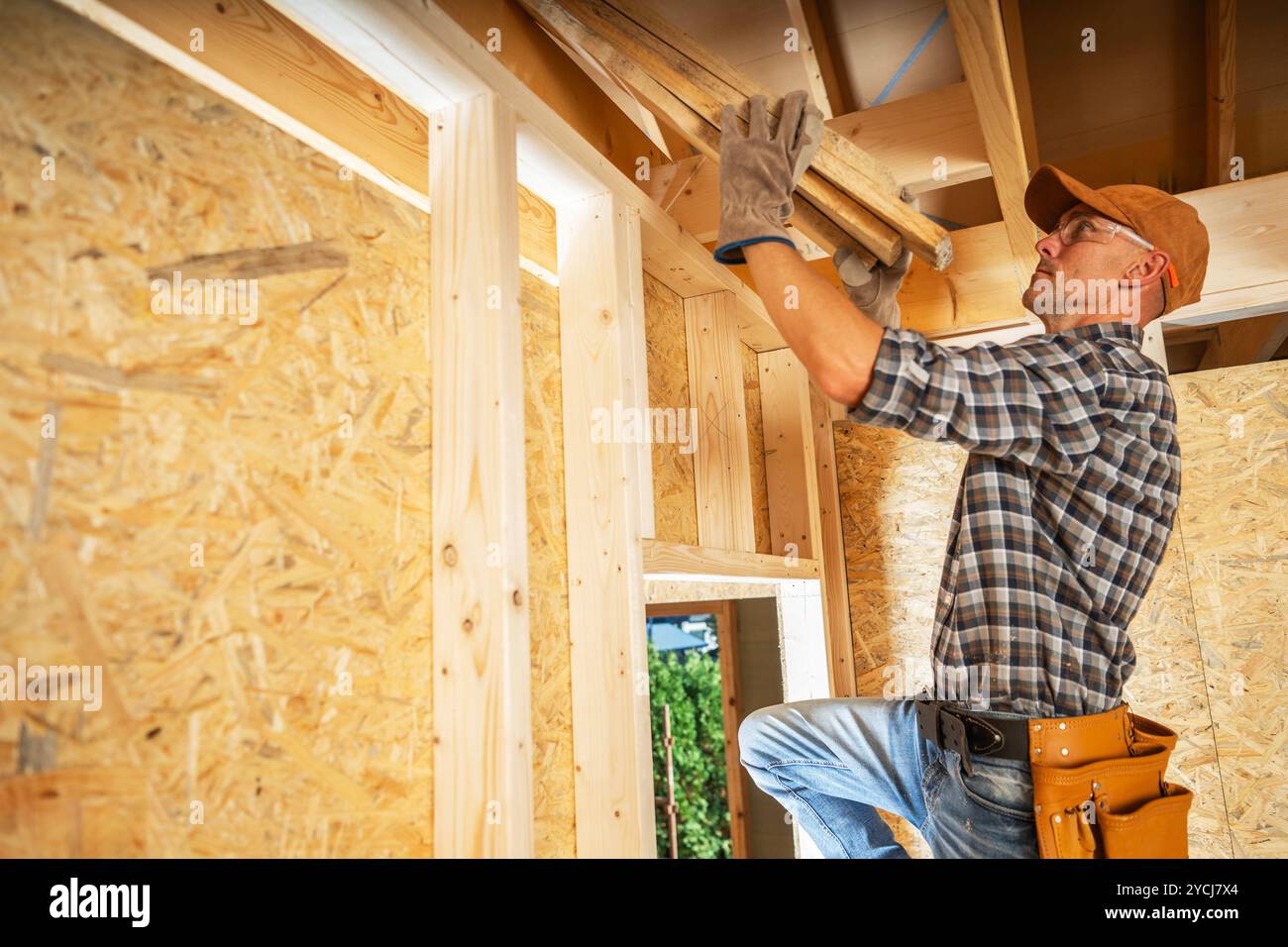 A skilled carpenter works diligently to install wooden beams in a construction project during ...