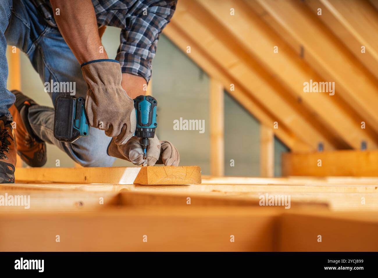 A skilled carpenter works diligently in an attic, securing wooden beams ...