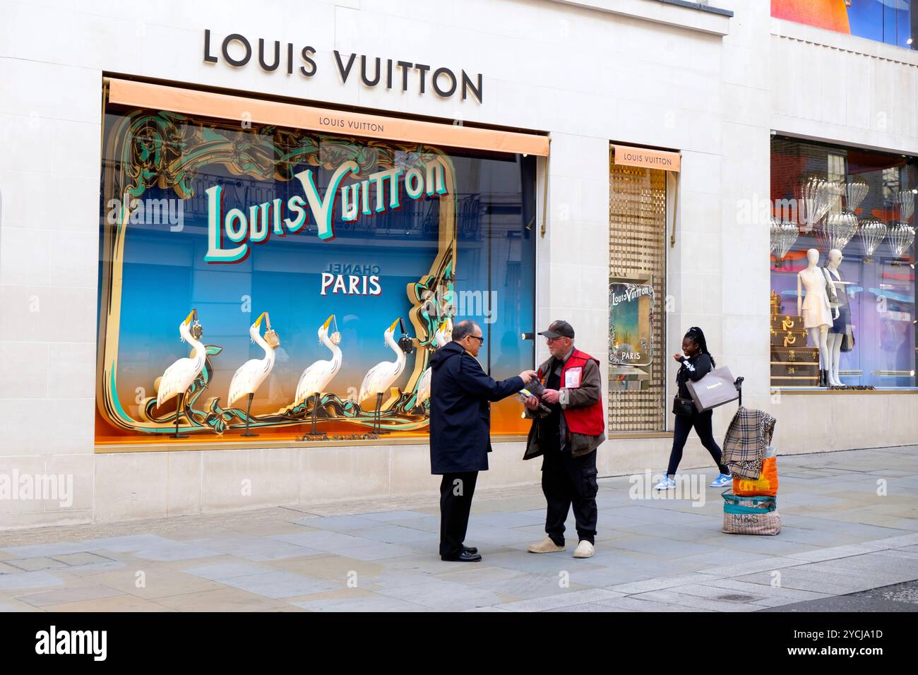 Exterior street view of shoppers Big Issue seller outside Louis Vuitton ...
