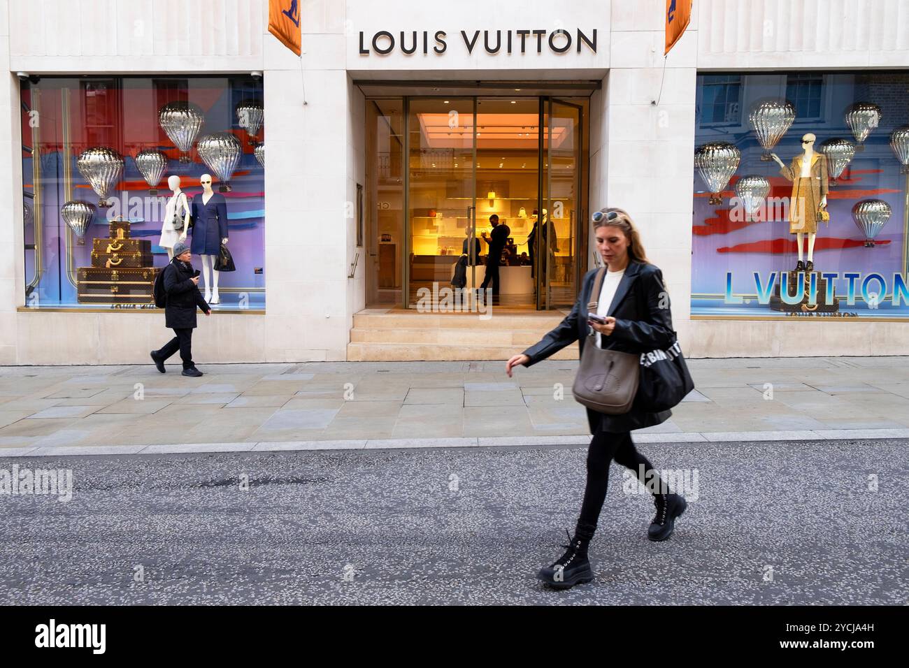 Exterior street view of shoppers Big Issue seller outside Louis Vuitton ...