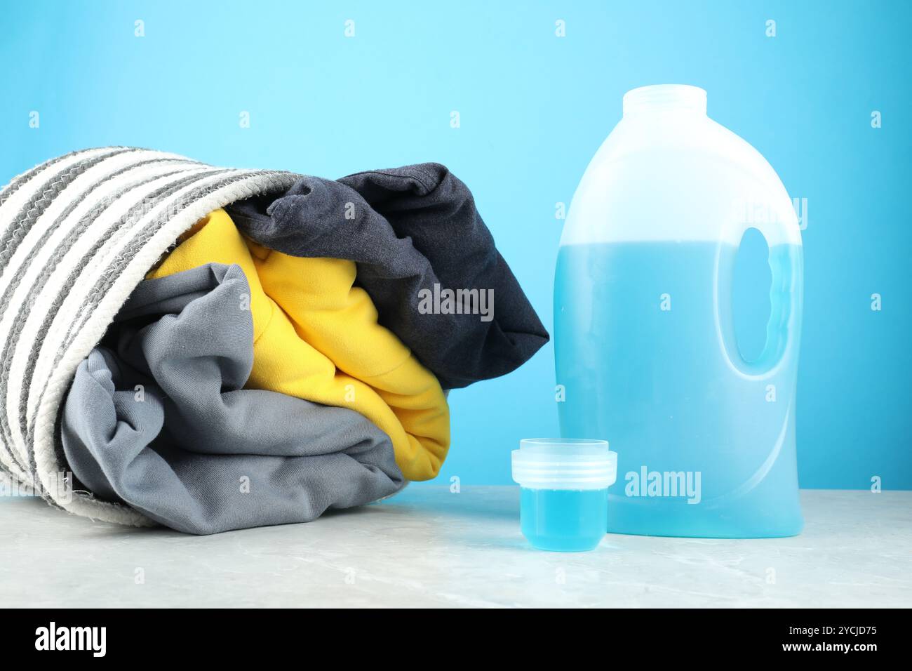Laundry detergent in bottle, cap and clothes on grey marble table ...