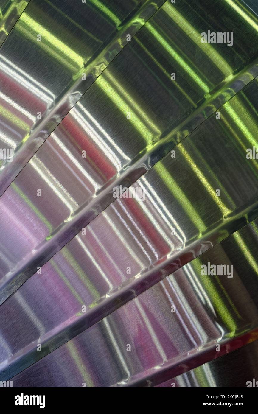 Multi-coloured light reflections on a curved surface made of brushed ...