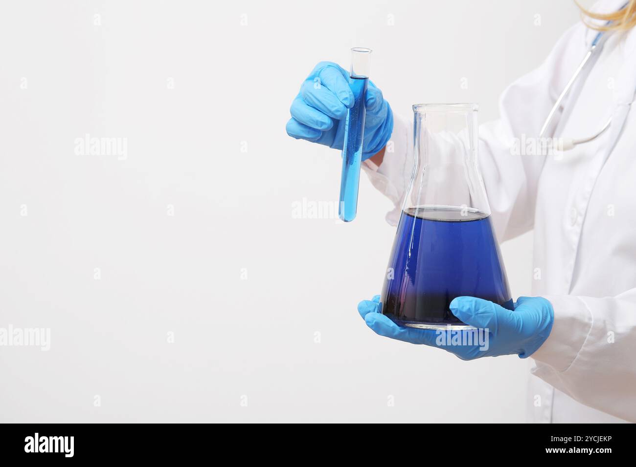 Female lab worker holding test tube and conical flask with sample on ...