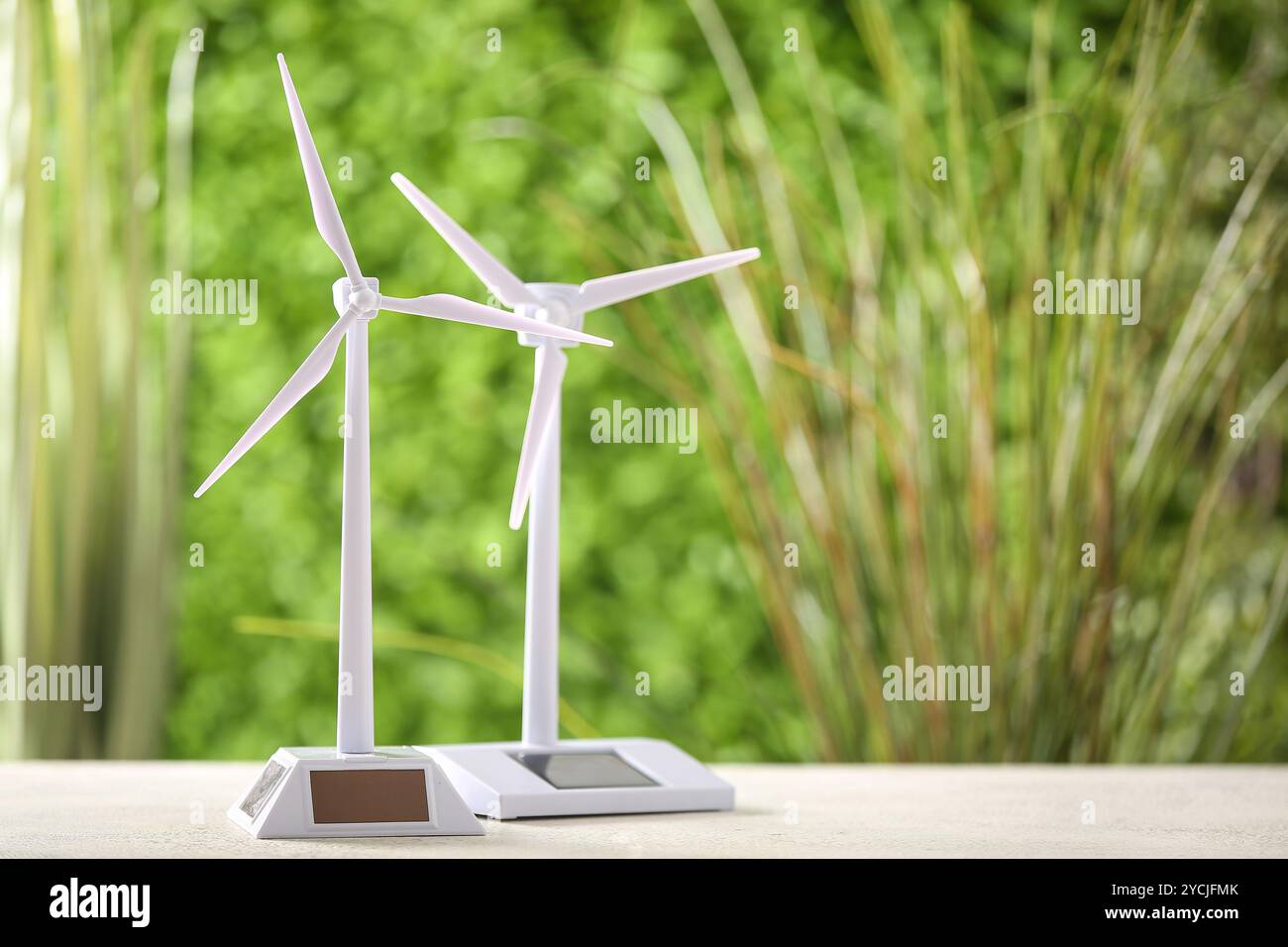 Wind turbine models on white table against green nature background ...