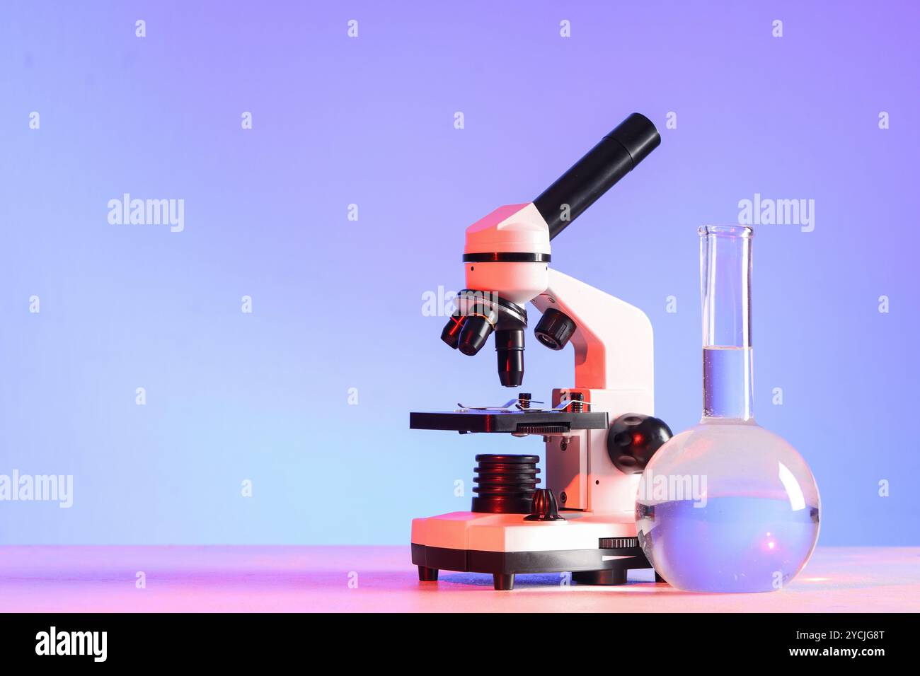 Modern microscope and laboratory flask with liquid on white table Stock ...