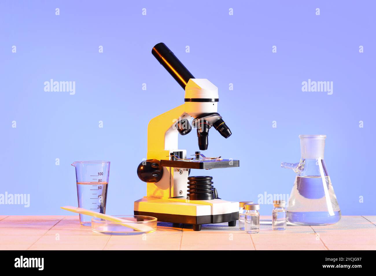 Modern microscope with laboratory glassware, spatula and ampules on ...