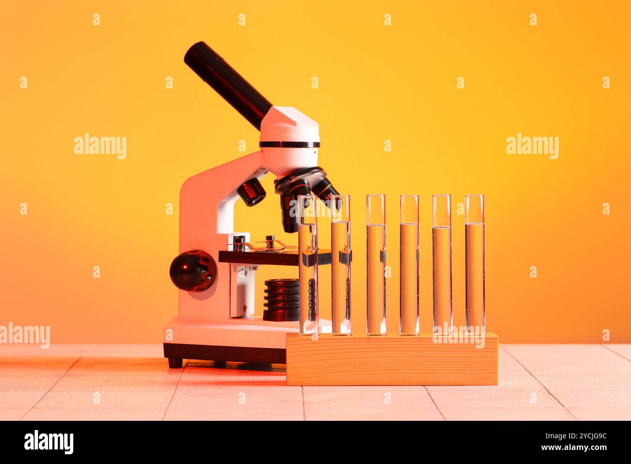 Holder with test tubes and modern microscope on white tile table Stock ...