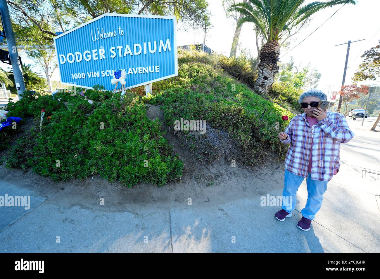 Gladys Sarmiento drops off a rose outside of Dodger Stadium after the ...
