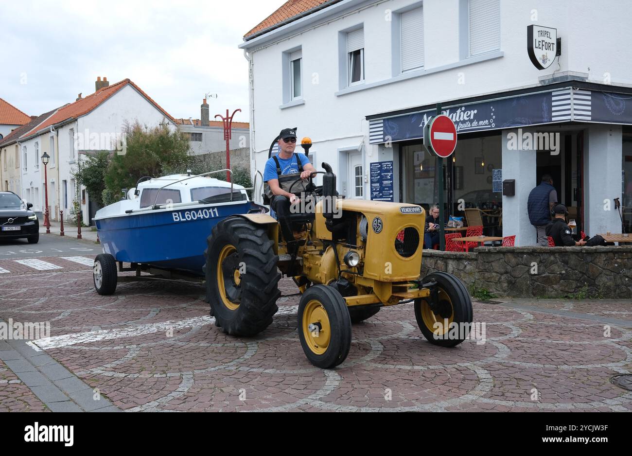 French fisherman towing his fishing boat with a vintage tractor through ...