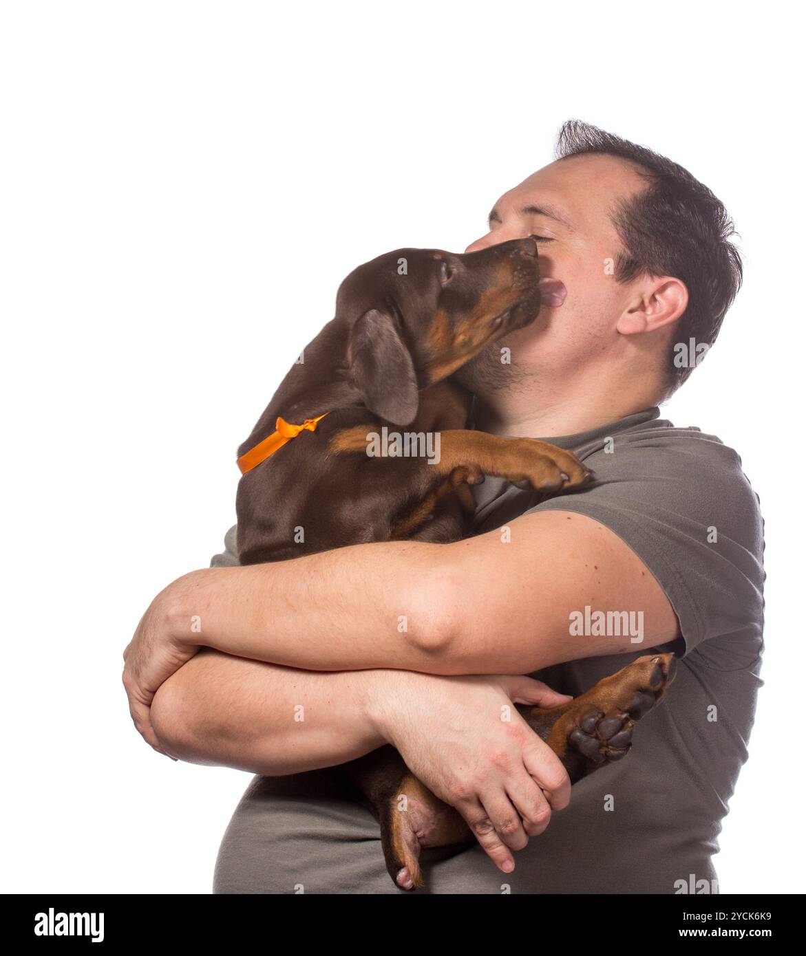 Young man is holding his sweet doberman puppy isolated on white ...