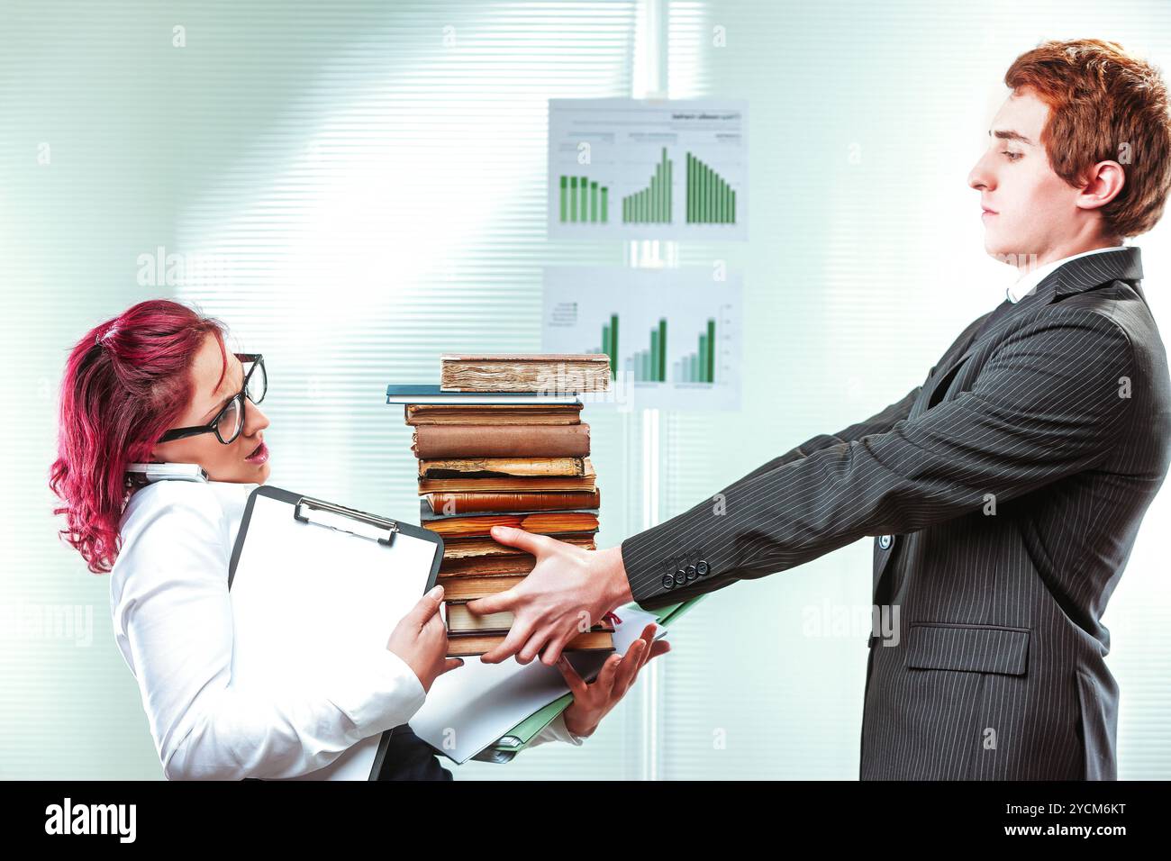 In an office setting, a woman struggles under the weight of books ...