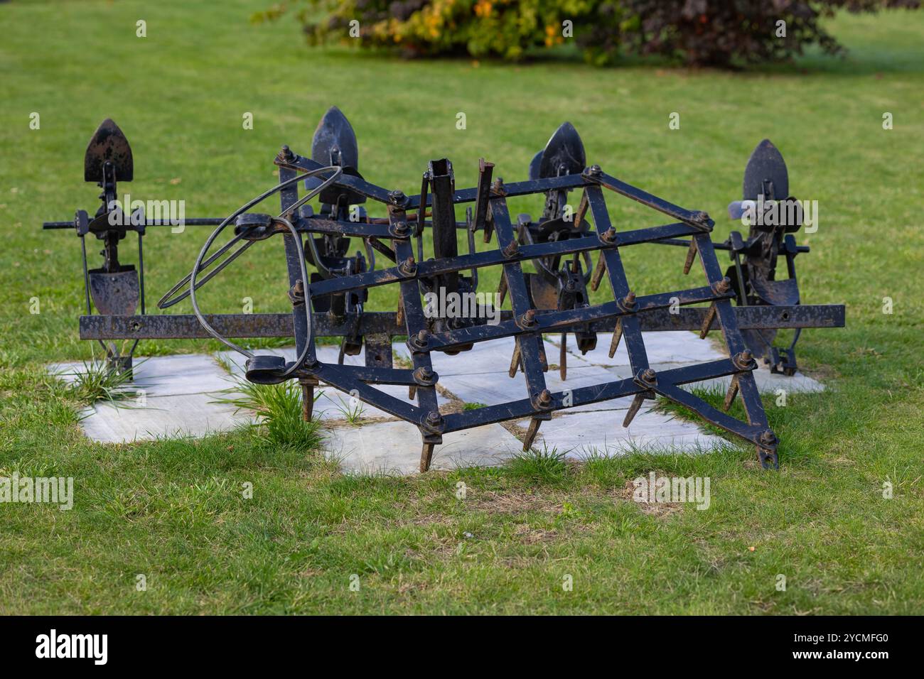 Vintage iron farming tool on display in green park on a sunny day ...