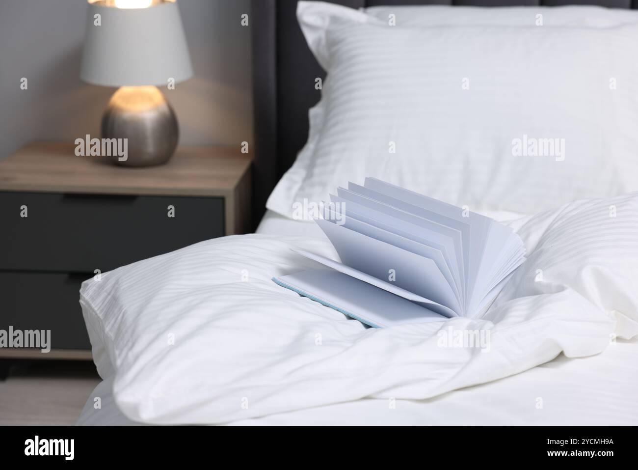 Open book on bed with clean linens indoors Stock Photo - Alamy