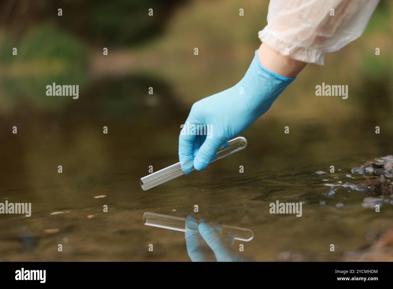 Examination of water quality. Researcher taking water sample from lake ...