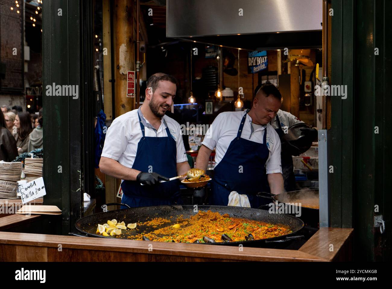 A male chef serving up Paella at Borough Market, London, England on the ...
