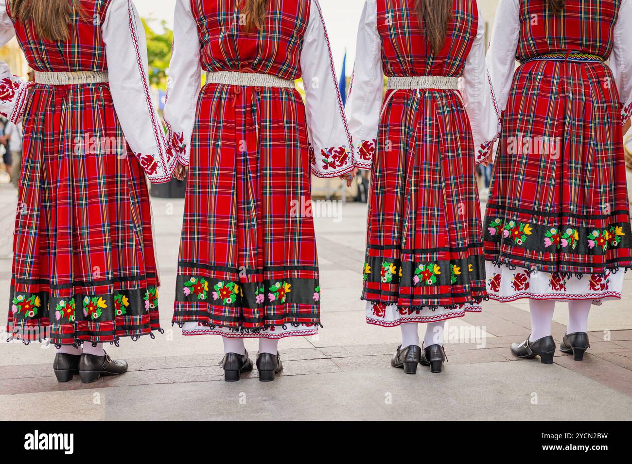 Back view of women in traditional red folk dresses during folk dance ...