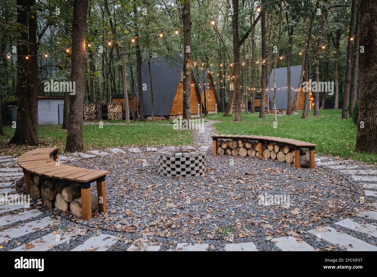 Cozy fire pit seating area in forest glamping with glowing string ...