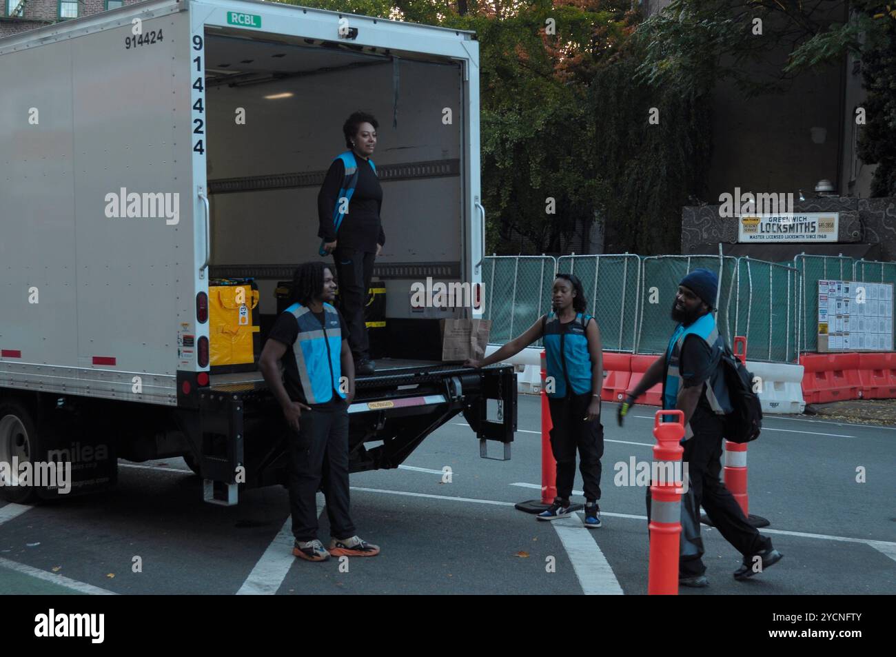 Amazon delivery workers are seen by a truck on the street in Manhattan ...