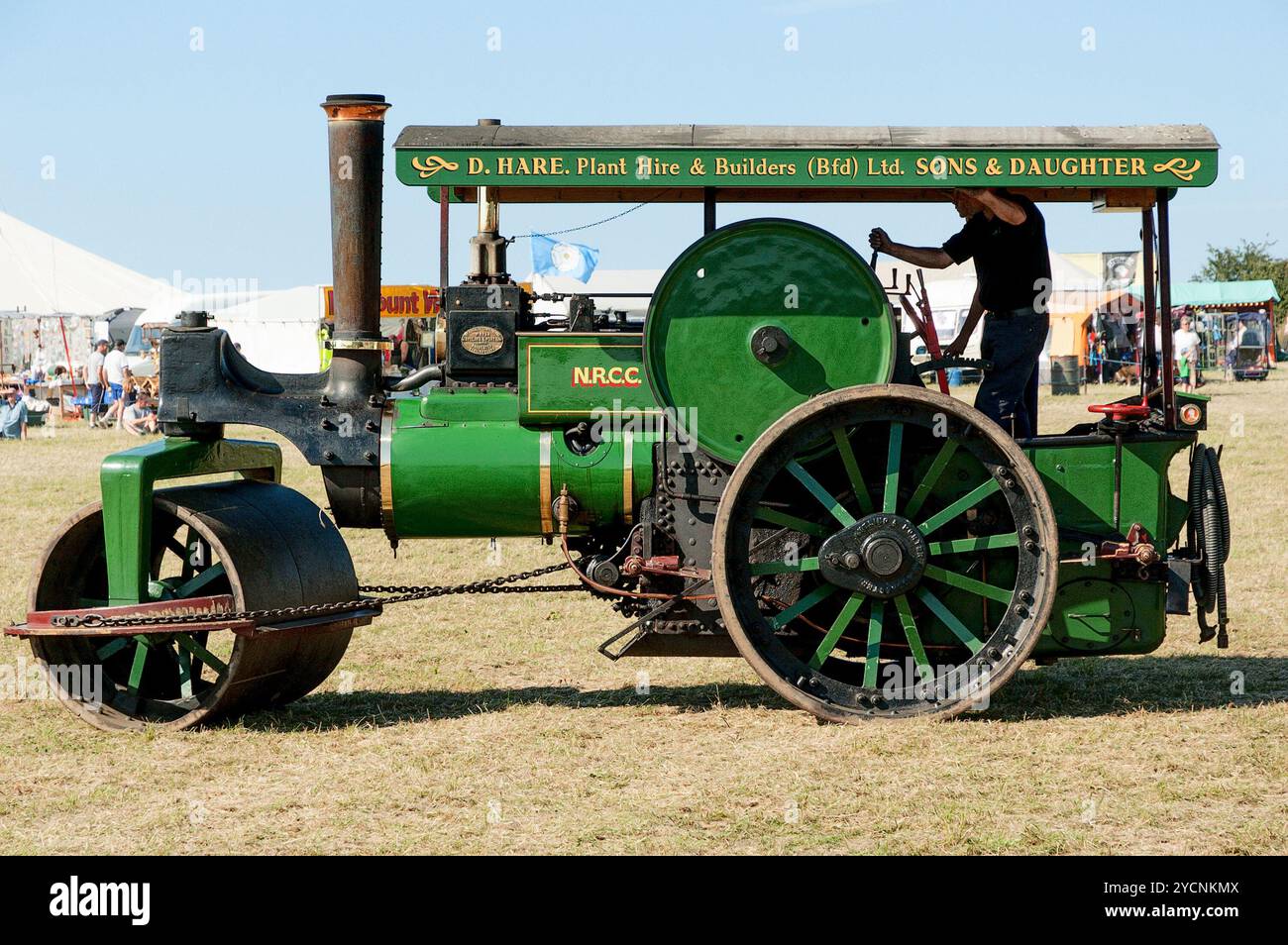 A green Aveling and Porter steam engine drives around the ring at the ...