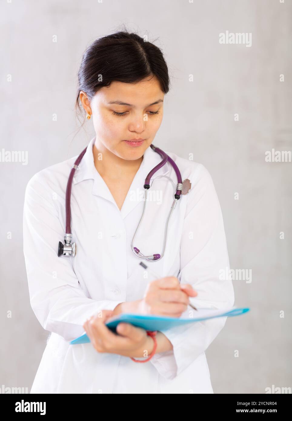 Female doctor in white uniform filling out medical form Stock Photo - Alamy