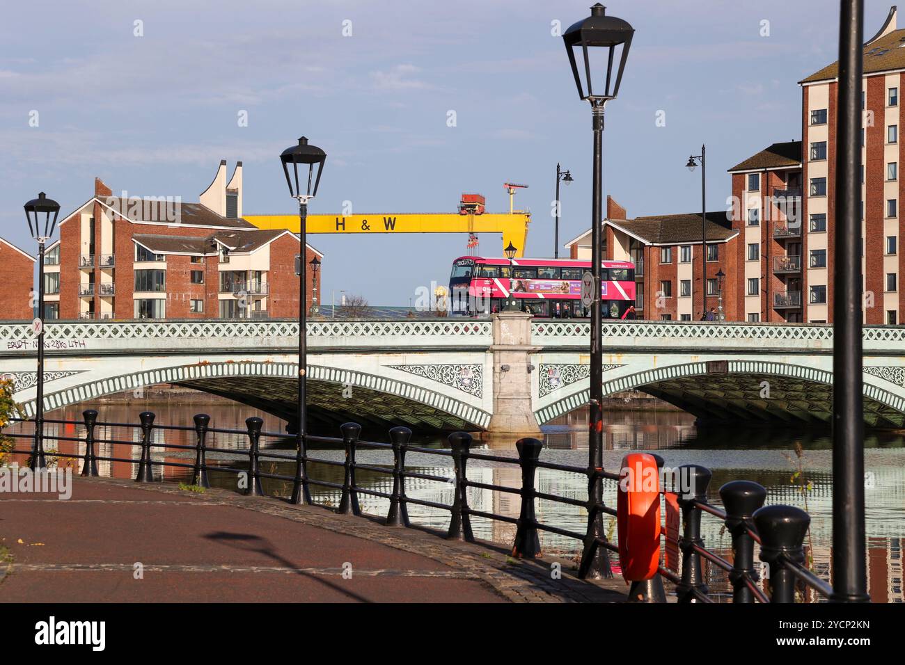 River walk beside River Lagan with Translink Metro bus crossing the Albert Bridge Belfast sunny ...