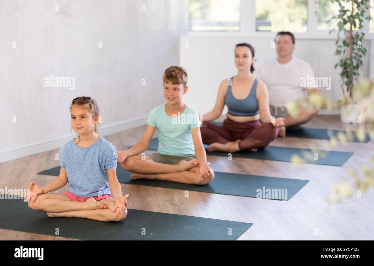Family with two children doing yoga in studio Stock Photo - Alamy