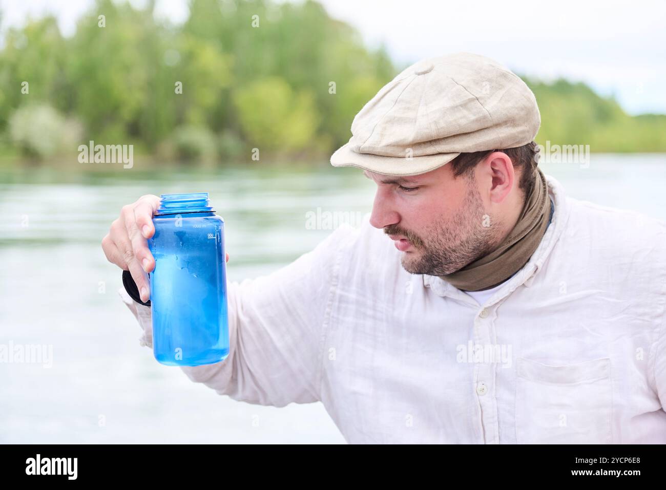 Man collecting water from a river in his bottle and looking at its ...