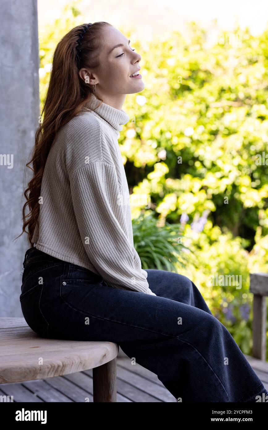 Woman enjoying sunshine on porch, smiling with eyes closed, feeling ...