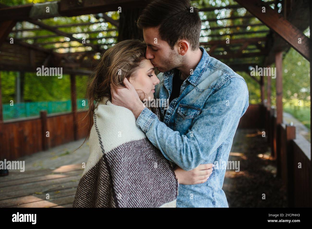 Young couple in love wrapped in plaid standing and kissing Stock Photo ...