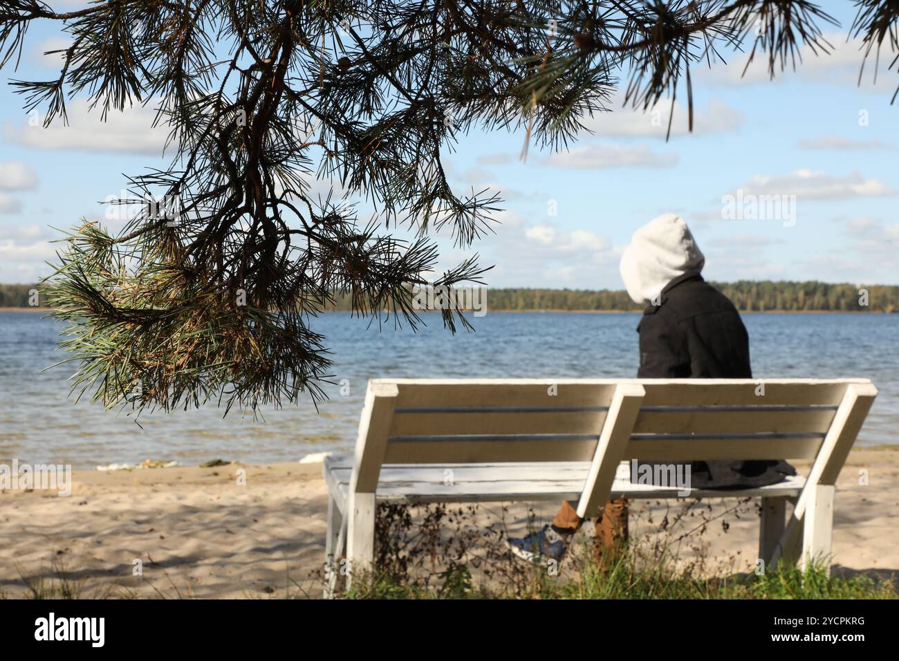 Loneliness concept. Sad man sitting on bench at riverside, selective ...