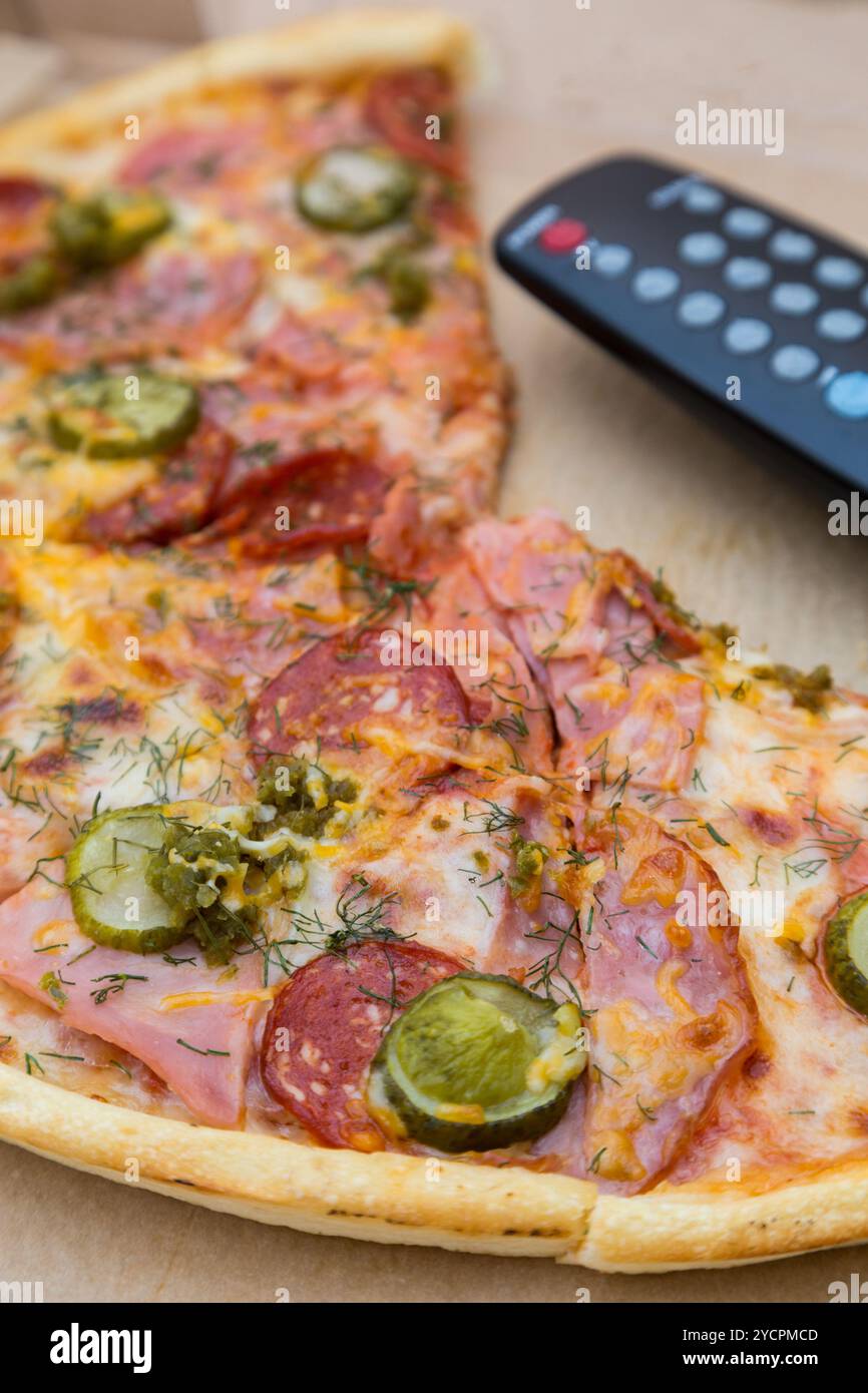 Pieces pizza in box with tv remote control Stock Photo - Alamy