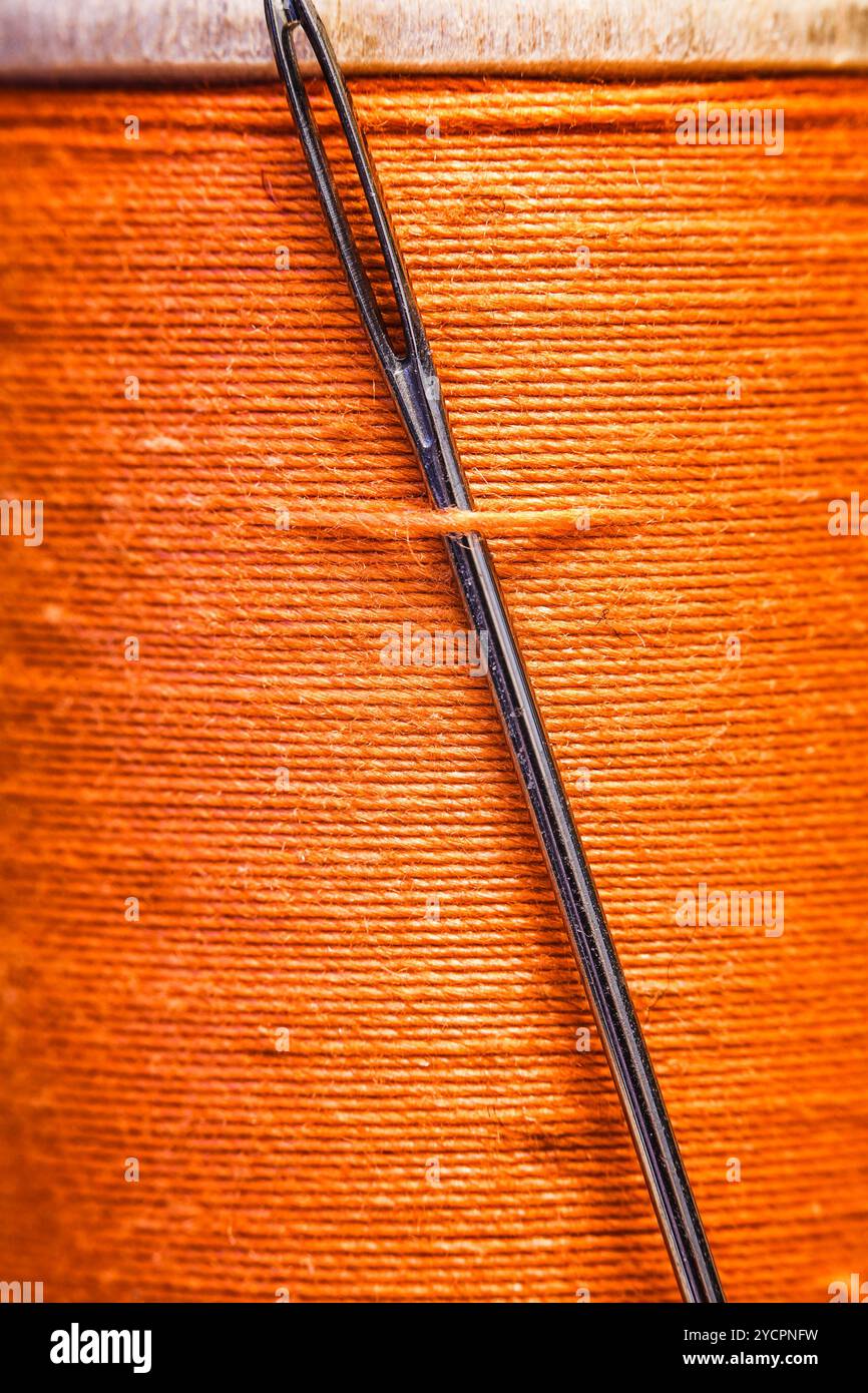 Spool of yellow thread with a needle stuck in it Stock Photo - Alamy