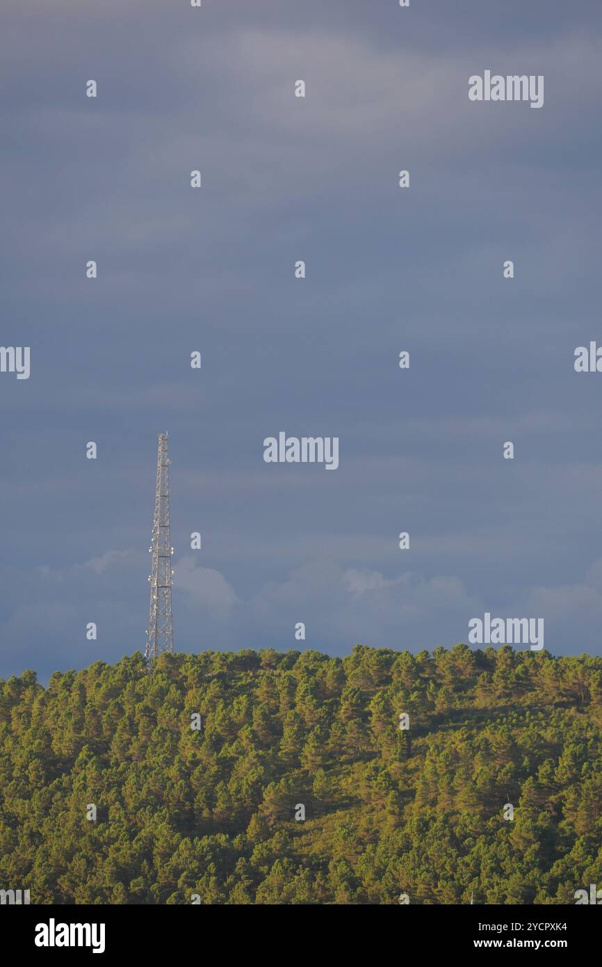 A Telecommunication Tower Standing Tall on a Lush Green Hill Beneath a Dramatic Sky Full of ...