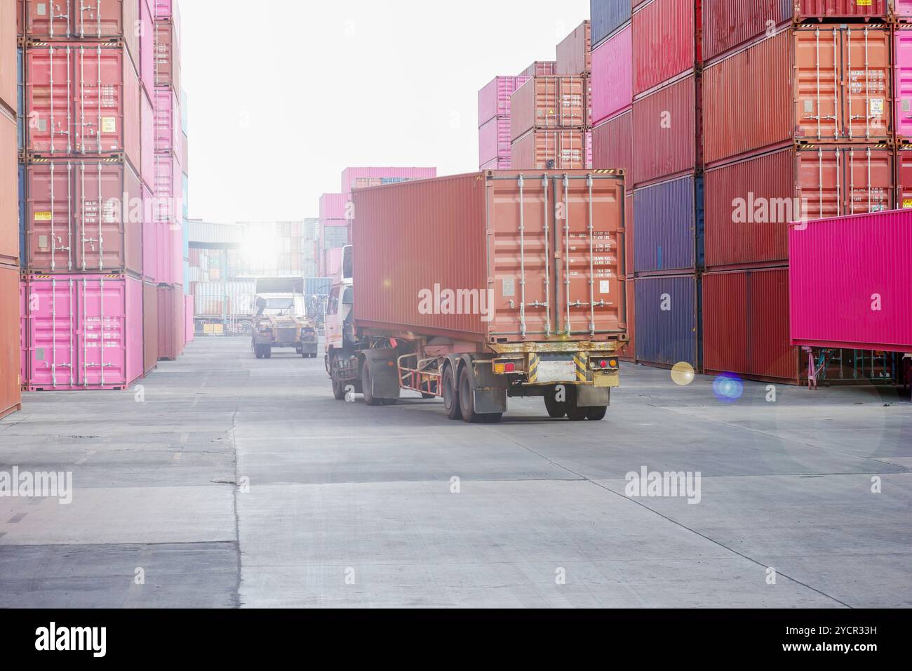 A container storage yard and forklifts are operating under a partly ...