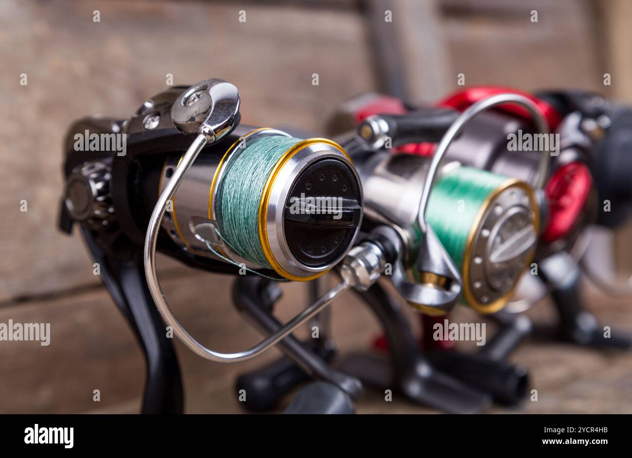 Different fishing reels with line on wooden background Stock Photo - Alamy