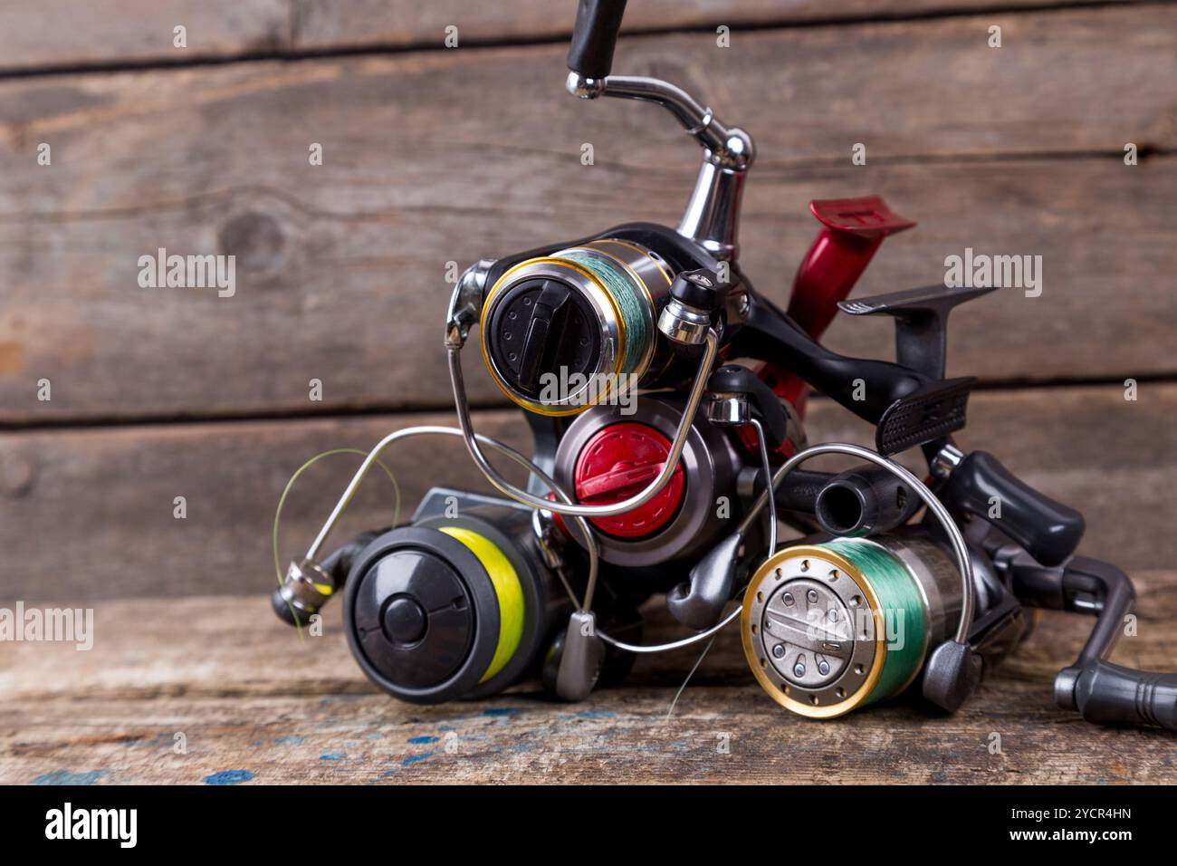 heap different fishing reels with line on wooden background. color ...