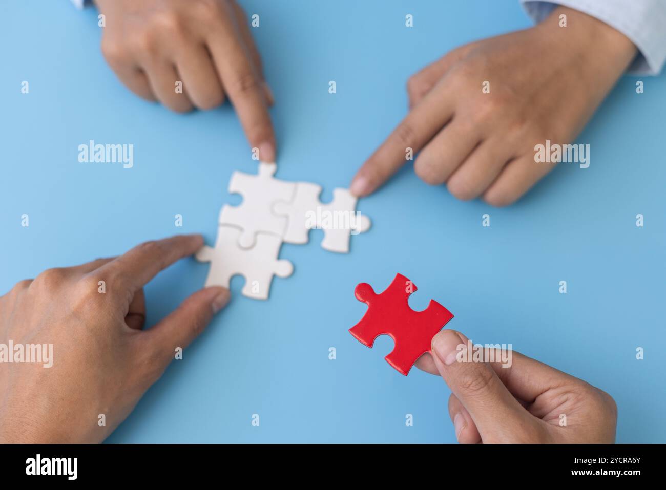 Business team holding parts of jigsaw puzzle trying to find solution to ...